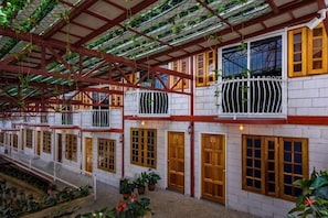 Um edifício coberto com várias varandas, portas de madeira e plantas em vasos.