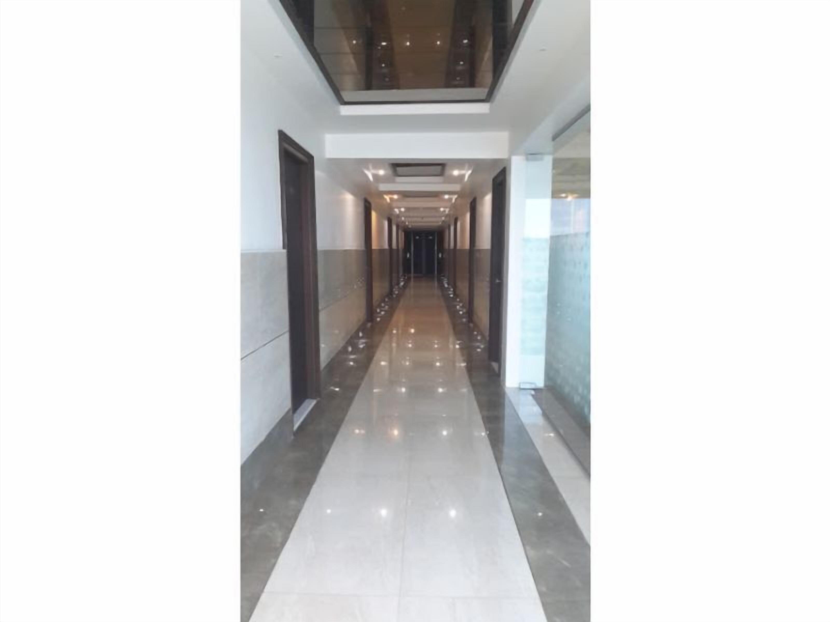 Um corredor comprido e estreito com piso espelhado, que leva a um teto de vidro.