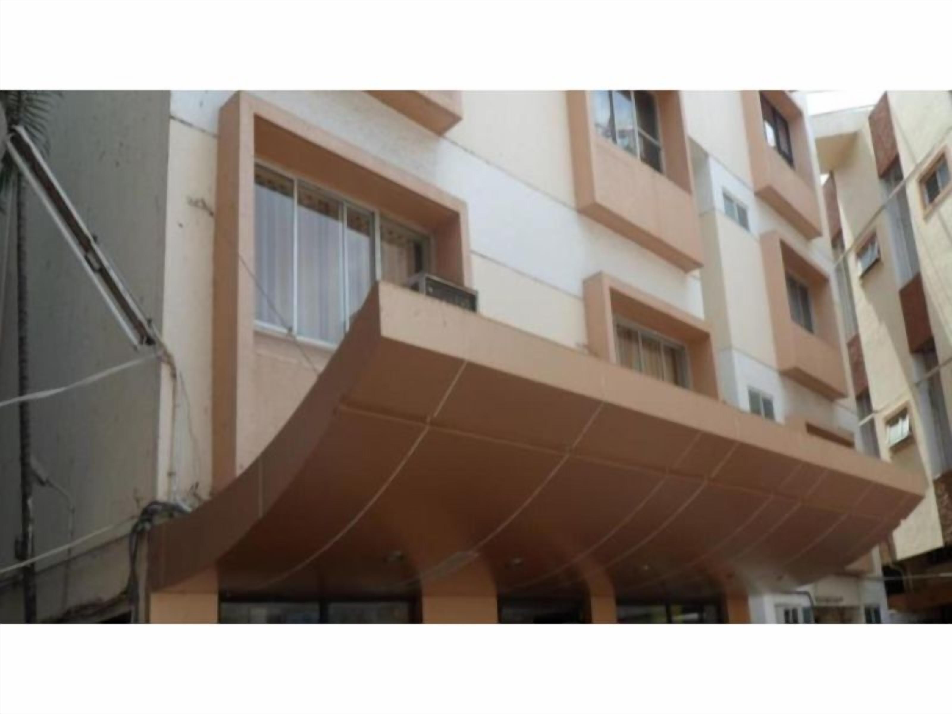 Um edifício de vários andares com telhado plano e área de entrada coberta.