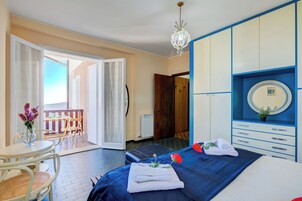 Quarto de hotel com cama, escrivaninha e varanda.