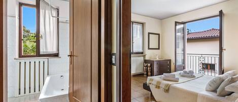 Quarto com cama grande, mesa de cabeceira, janela e vista para o exterior.
