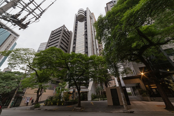 Uma rua urbana moderna com edifícios altos, árvores e céu claro.