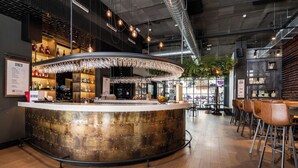 Uma área de bar moderna com balcão curvo, luminárias pendentes e variedade de garrafas e copos.