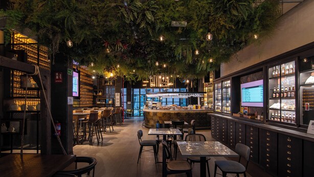 Uma área de bar com balcão, assentos e um painel de exibição do cardápio.