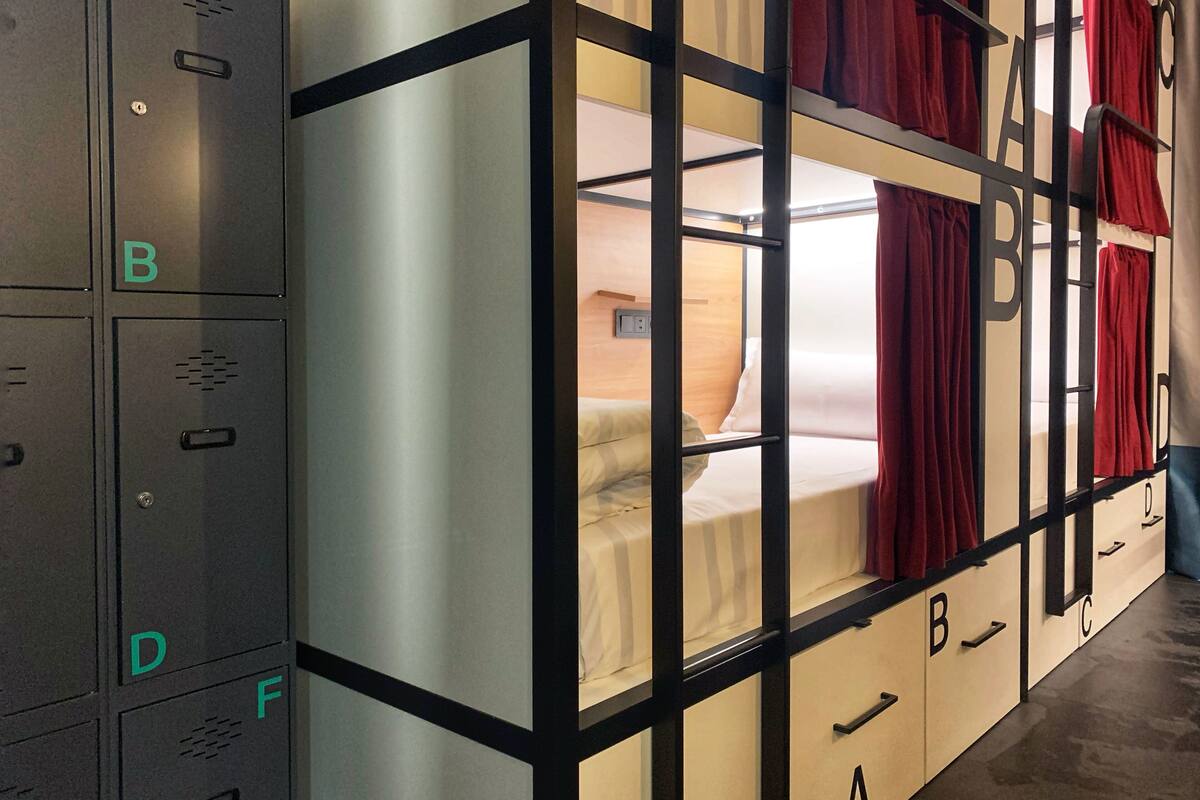 Quarto com beliche e guarda-roupa de metal com as letras B, C e D.