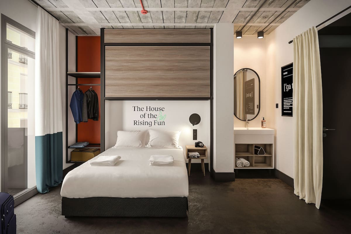 Quarto de hotel moderno com uma cama grande, um guarda-roupa, uma toucador com espelho e vista para a varanda.