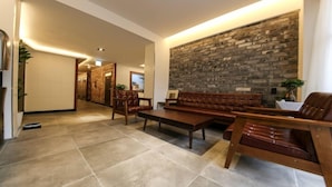 Um lobby moderno com parede de pedra, assentos de couro e piso ladrilhado.