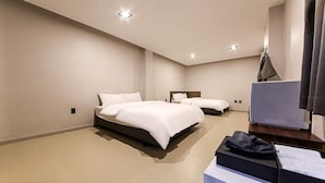 Quarto de hotel com duas camas, uma escrivaninha com um computador portátil e uma televisão.