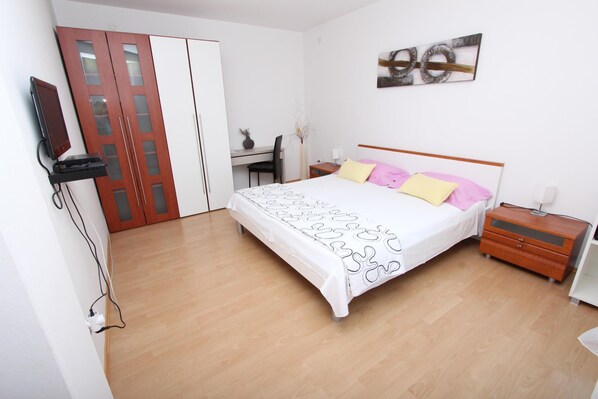 Quarto com cama, mesas de cabeceira, escrivaninha e guarda-roupa.