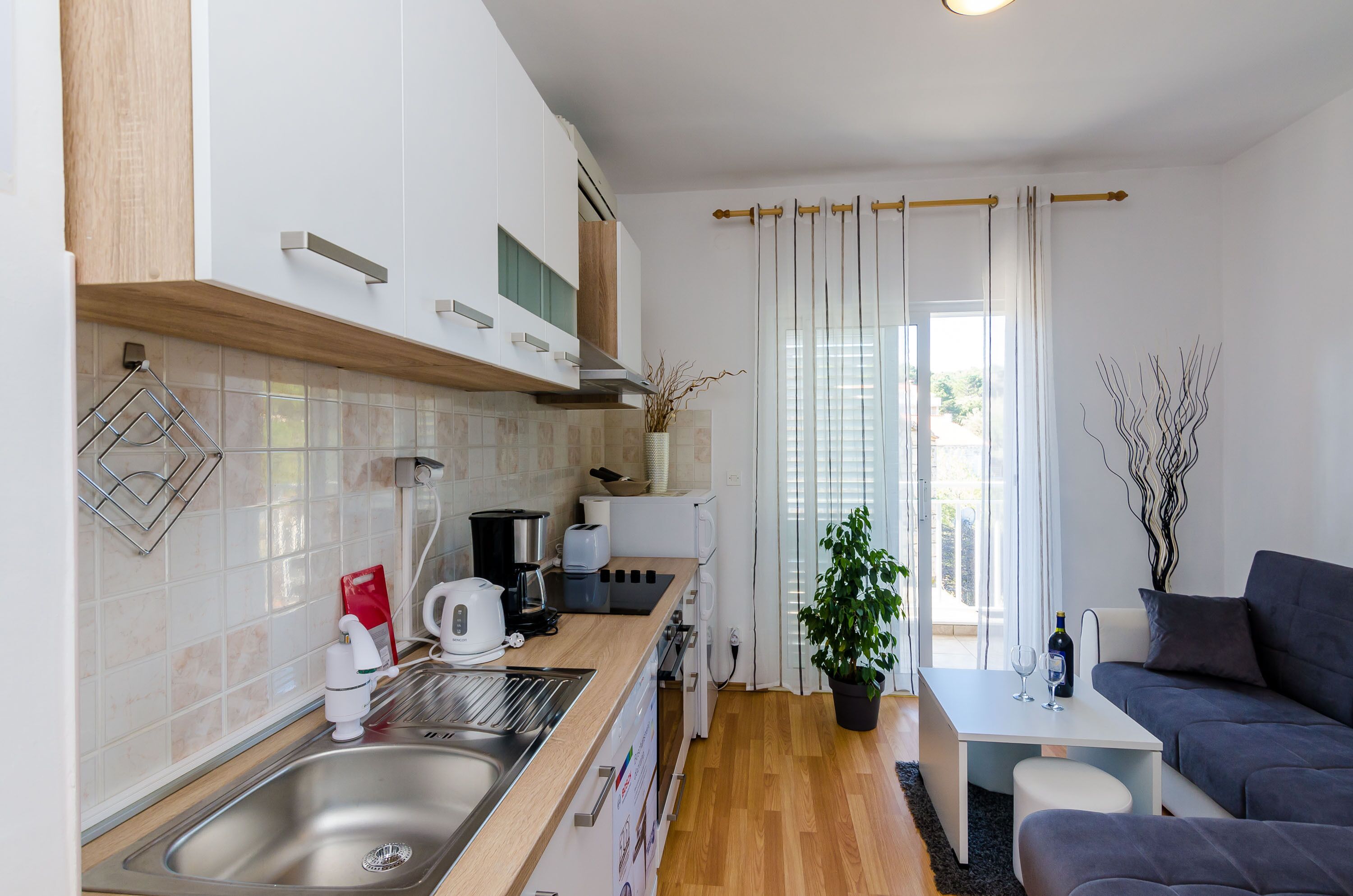 Uma cozinha compacta com eletrodomésticos modernos, sala de jantar com mesa e cadeiras, e sala de estar com sofá.