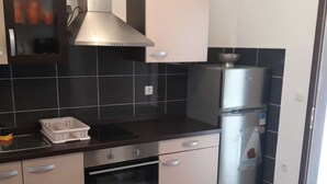 Uma cozinha moderna com armários pretos e bege, eletrodomésticos de aço inoxidável e painel de azulejos.