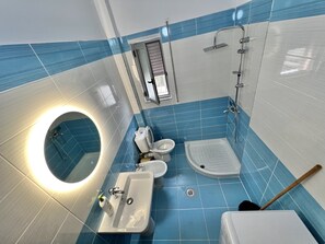 Casa de banho compacta com lavatório, sanita e chuveiro.