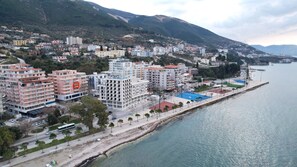 Paisagem costeira com edifícios residenciais, uma praia e montanhas ao fundo.