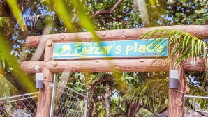 Uma placa de madeira com o texto 'Bem-vindo ao Ceazar's Place à Beira-Mar'.