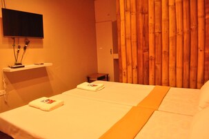 Quarto de hotel com uma cama, televisão de tela plana na parede e painel de parede de madeira.
