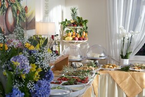 Mesa de buffet com diversos alimentos e uma exposição de frutas.