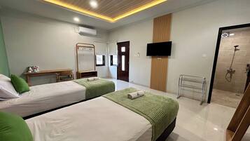 Quarto de hotel com duas camas, televisão, chuveiro e uma pequena mesa com uma cadeira.