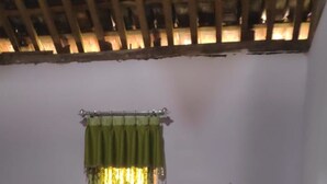 Quarto com cortina verde, radiador e lixeira.