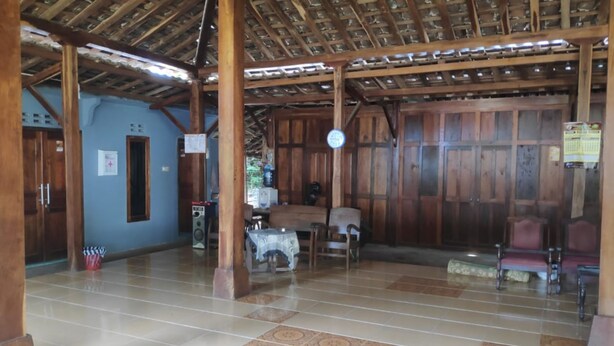Interior de madeira com chão ladrilhado, um relógio e uma mesa com cadeiras.