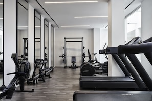 Uma academia moderna com equipamentos de cardio, aparelhos de musculação e halteres.