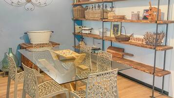 Uma sala de jantar com uma mesa de madeira, cadeiras transparentes e uma prateleira fixada na parede com diversos objetos.