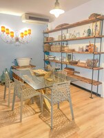 Uma sala de jantar com uma mesa de madeira, cadeiras transparentes e uma prateleira fixada na parede com diversos objetos.