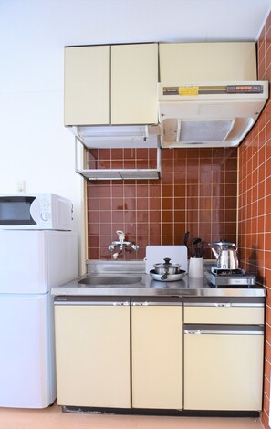 Uma cozinha compacta com micro-ondas, pia e fogão.