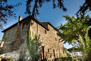 Um edifício de pedra com varanda de madeira, cercado por árvores.