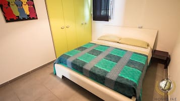 Quarto com cama, janela, guarda-roupa amarelo e um quadro na parede.