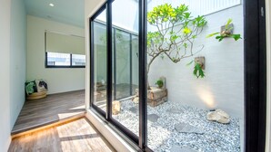 Decoração moderna com porta de vidro que dá para um jardim com pedras e plantas.