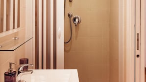 Uma casa de banho moderna com lavatório branco, espelho e cabine de duche.