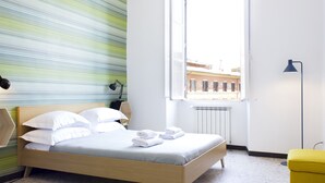 Quarto de hotel moderno com cama, janela, radiador e uma cadeira amarela.