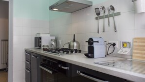 Cozinha moderna com eletrodomésticos de aço inoxidável, fogão a gás, chaleira e torradeira.