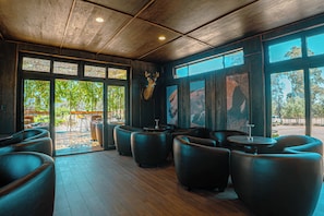 Interior de restaurante com teto de madeira, janelas amplas e assentos de couro.
