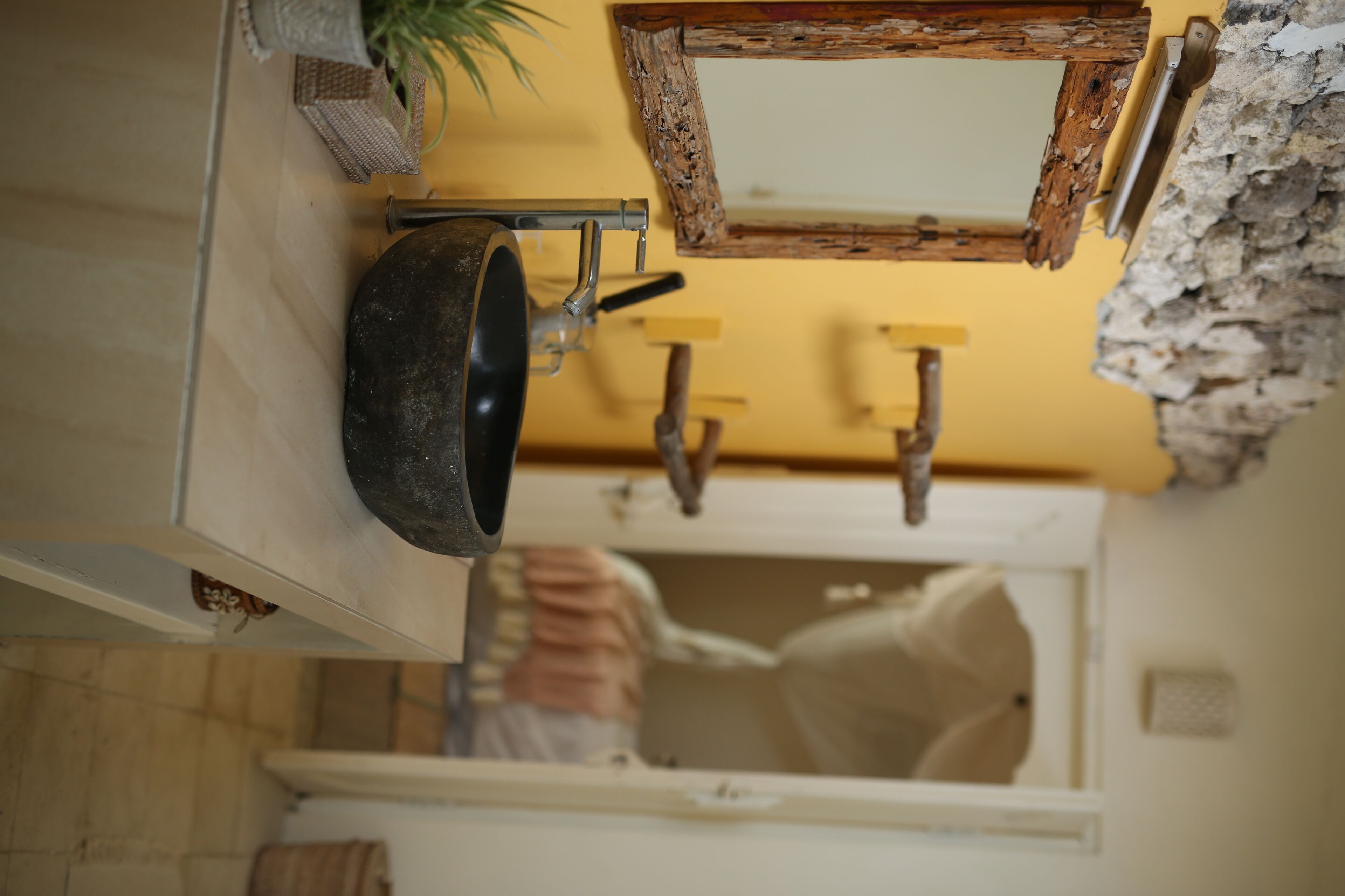 Cozinha com design rústico, incluindo um espelho com moldura de madeira, um suporte para panelas pendurado e uma parede com detalhes em pedra.