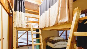 Quarto estilo dormitório com beliches, escada e janela com persianas de madeira.