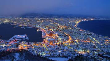 Paisagem urbana noturna com edifícios cobertos de neve e uma orla costeira.