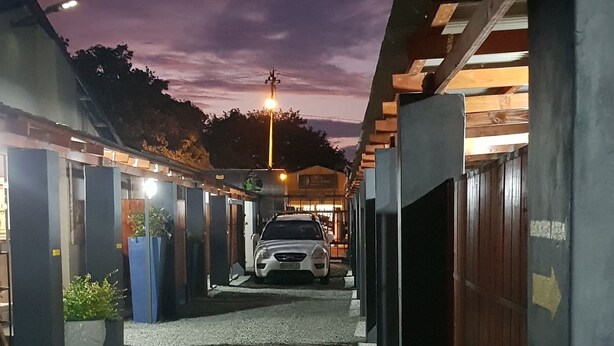 Uma garagem de estacionamento com um carro no centro, rodeado por pilares de concreto e vigas de madeira.