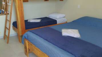Quarto com duas beliches, uma cama de solteiro, móveis de madeira e uma escada.