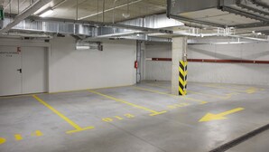 Garagem de estacionamento com vagas demarcadas, extintor de incêndio e sistema de ventilação.