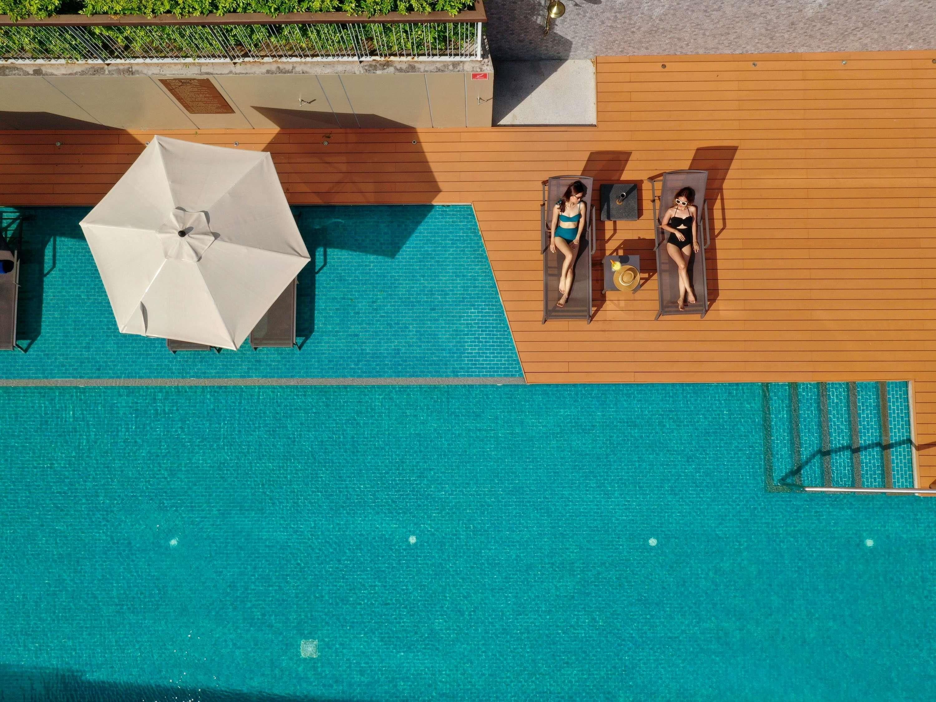 Vista aérea de uma área de piscina com duas espreguiçadeiras e um grande guarda-sol.