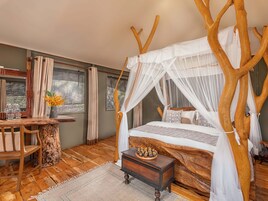 Quarto com cama de dossel, mobiliário de madeira e vista para o exterior.