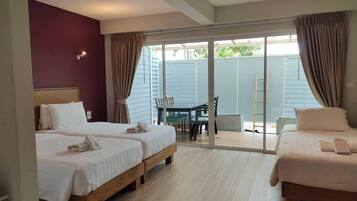 Quarto de hotel com duas camas, uma mesa de jantar e uma porta de vidro que se abre para uma área externa.