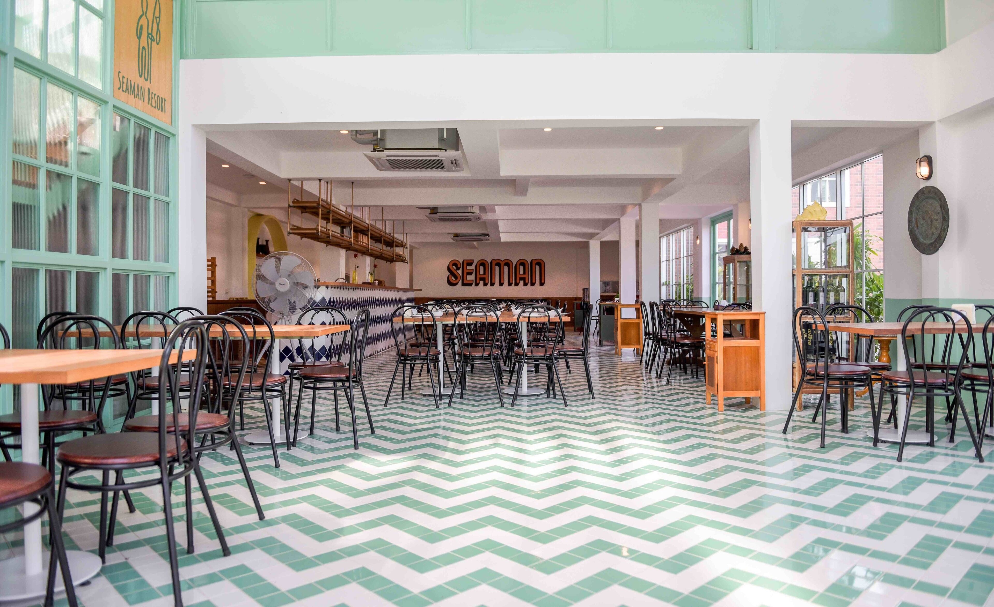 Um restaurante amplo com uma longa mesa comunitária, diversas áreas de estar e design de interiores moderno.