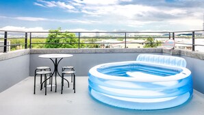 Terraço ao ar livre com piscina inflável azul, uma mesa redonda e duas cadeiras.