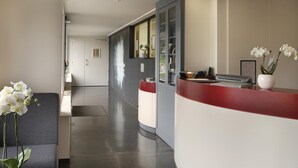 Uma área de recepção com balcão, espaço de estar com sofá e um vaso de planta.