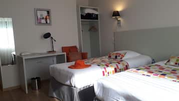 Quarto de hotel com duas camas, uma escrivaninha com luminária, um guarda-roupa e uma pequena lixeira.
