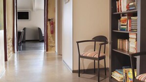 Um corredor com uma estante, uma cadeira e um extintor de incêndio.