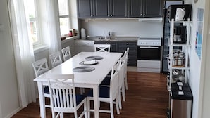 Uma cozinha moderna com armários brancos, uma mesa de jantar com cadeiras e uma máquina de café.