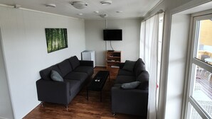 Uma sala de estar moderna com dois sofás escuros, uma mesa de centro, uma TV de tela plana e uma pintura na parede.